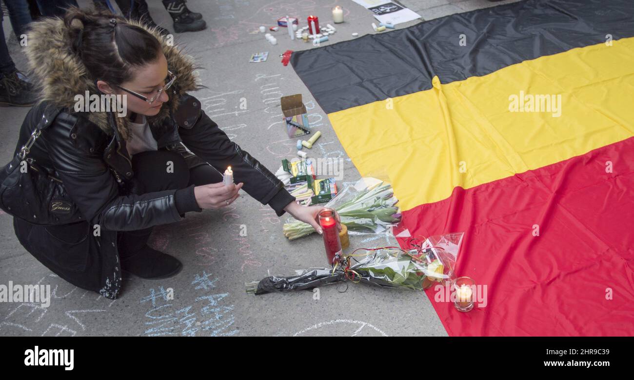A woman places a candle next to a Belgium flag during a vigil at the ...
