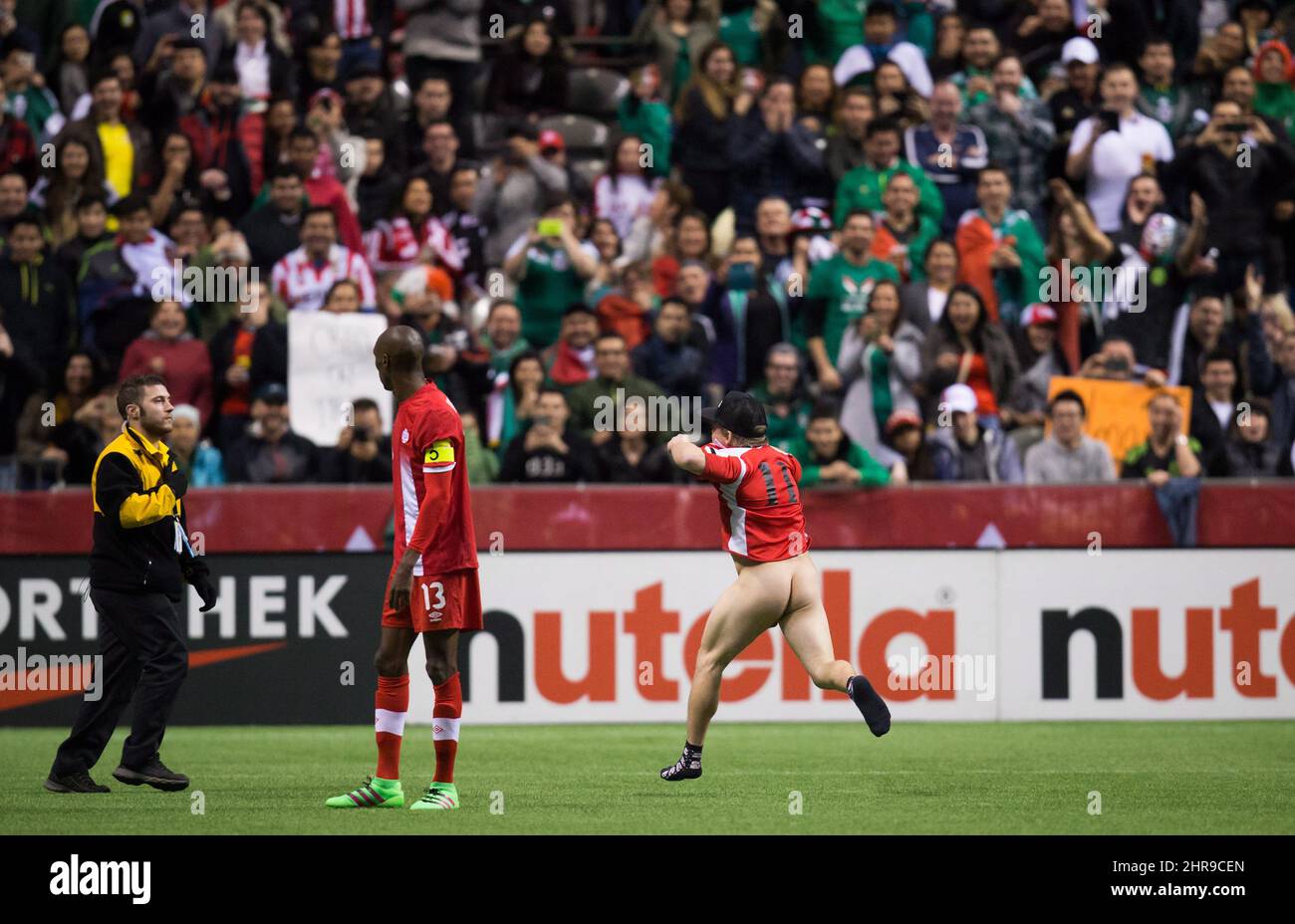 A streaker runs past Canada's Atiba Hutchinson as they play Mexico ...
