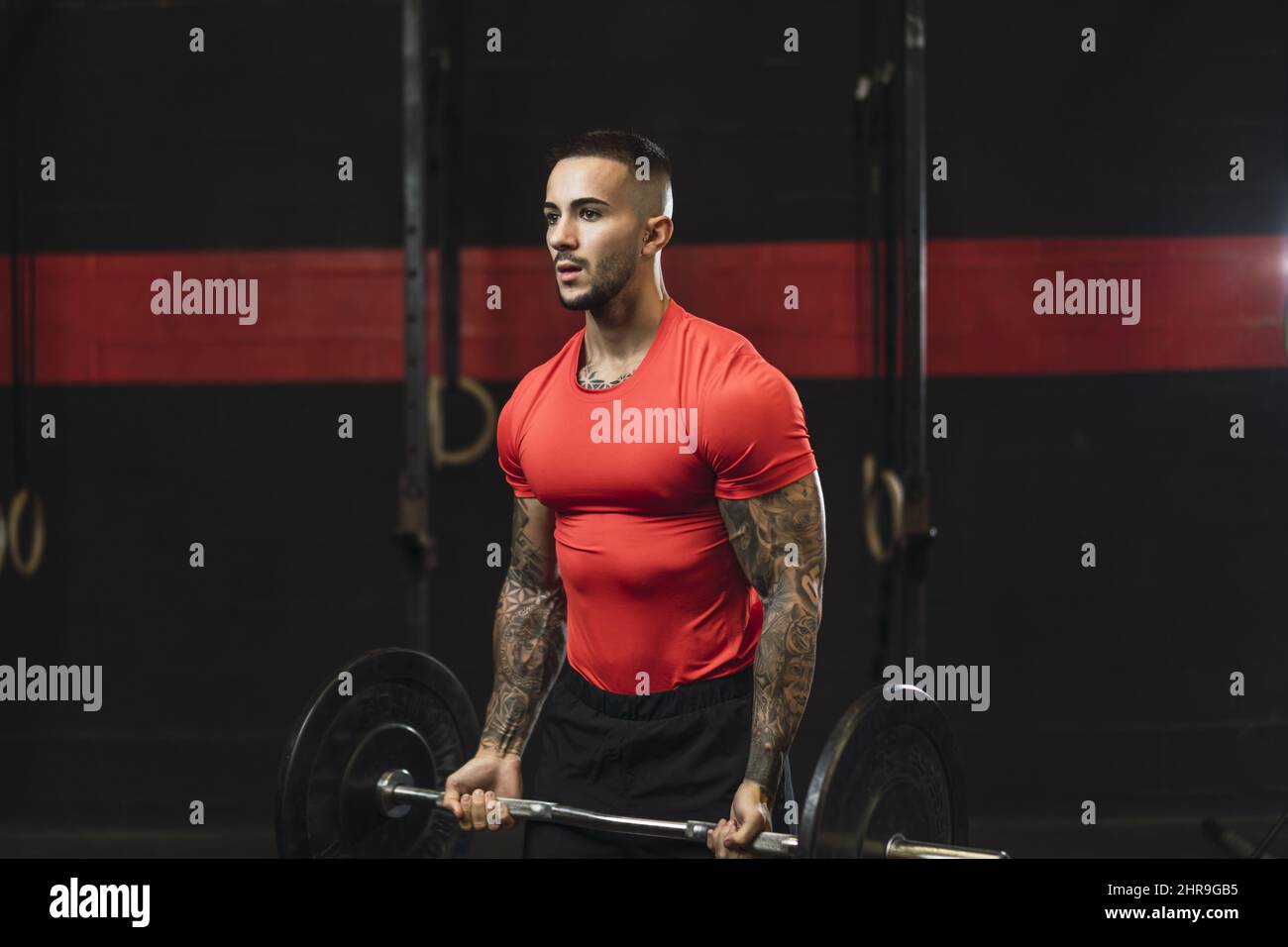Strong muscular European guy with cool tattoos working out in a gym ...