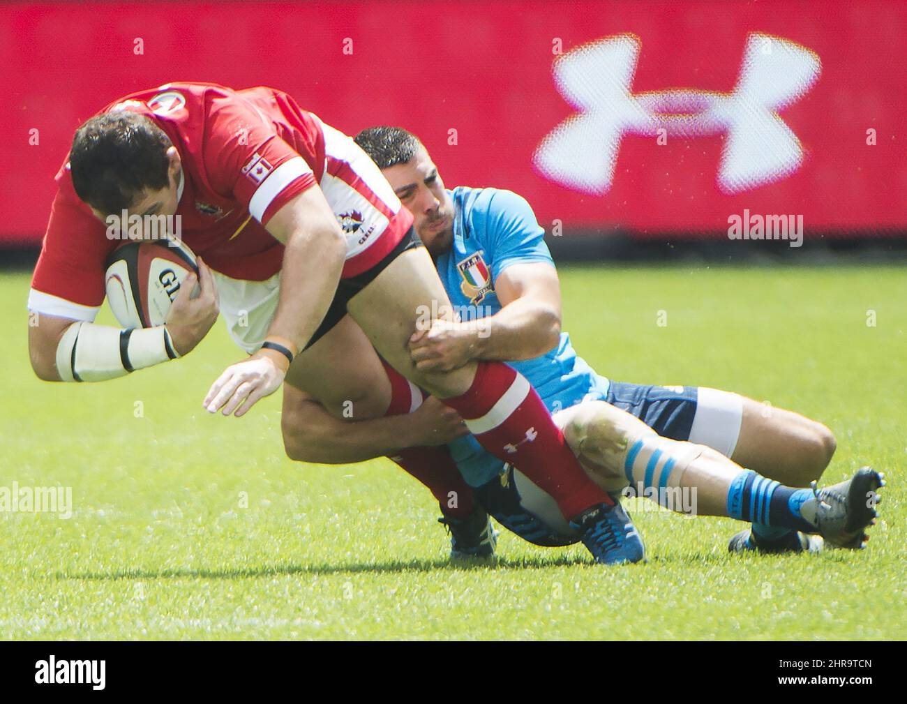 Canada's Aaron Carpenter, left, gets tackled by Italy's Edoardo Gori ...