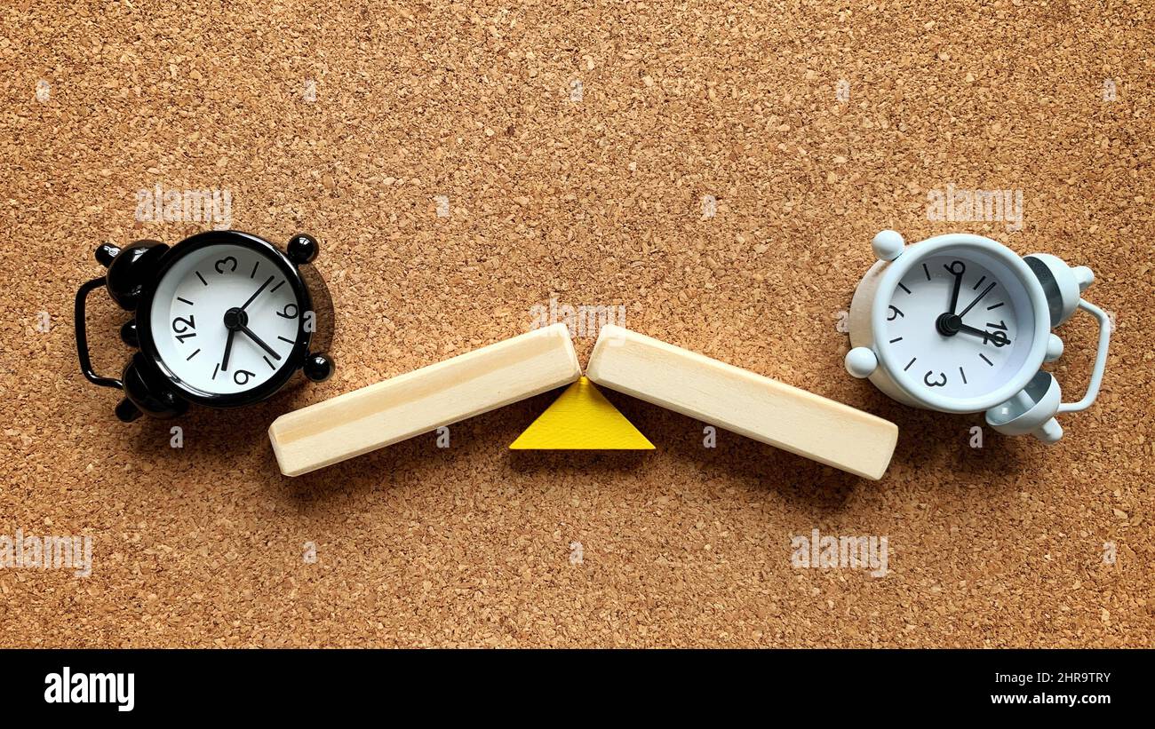 Alarm clocks on a wooden seesaw, both side fall. Success and failure ...