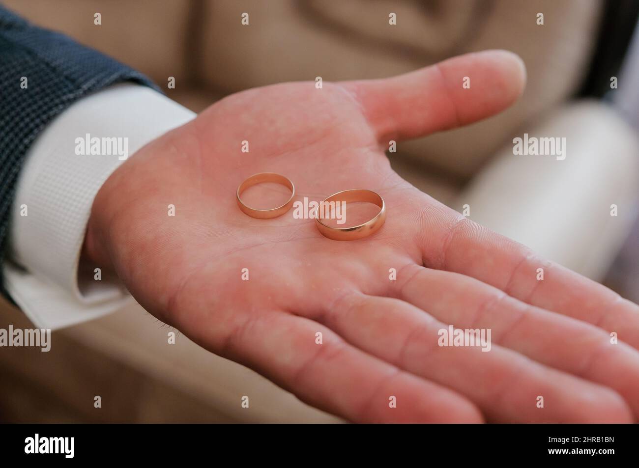 A pair of wedding gold rings in the hands of the groom. Wedding rings ...