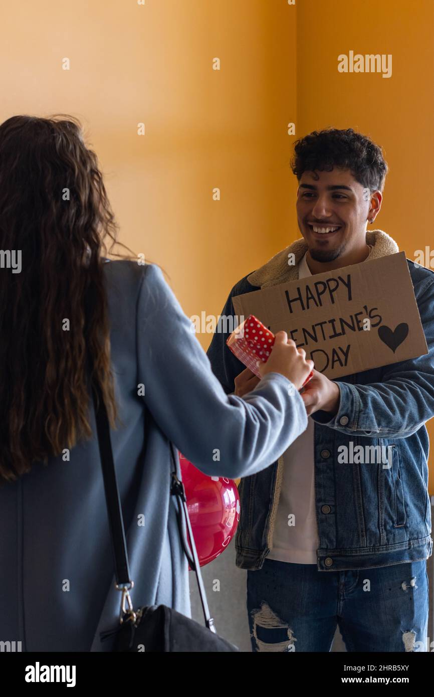 Vertical of a smiling Hispanic male giving a surprise to a girl for ...
