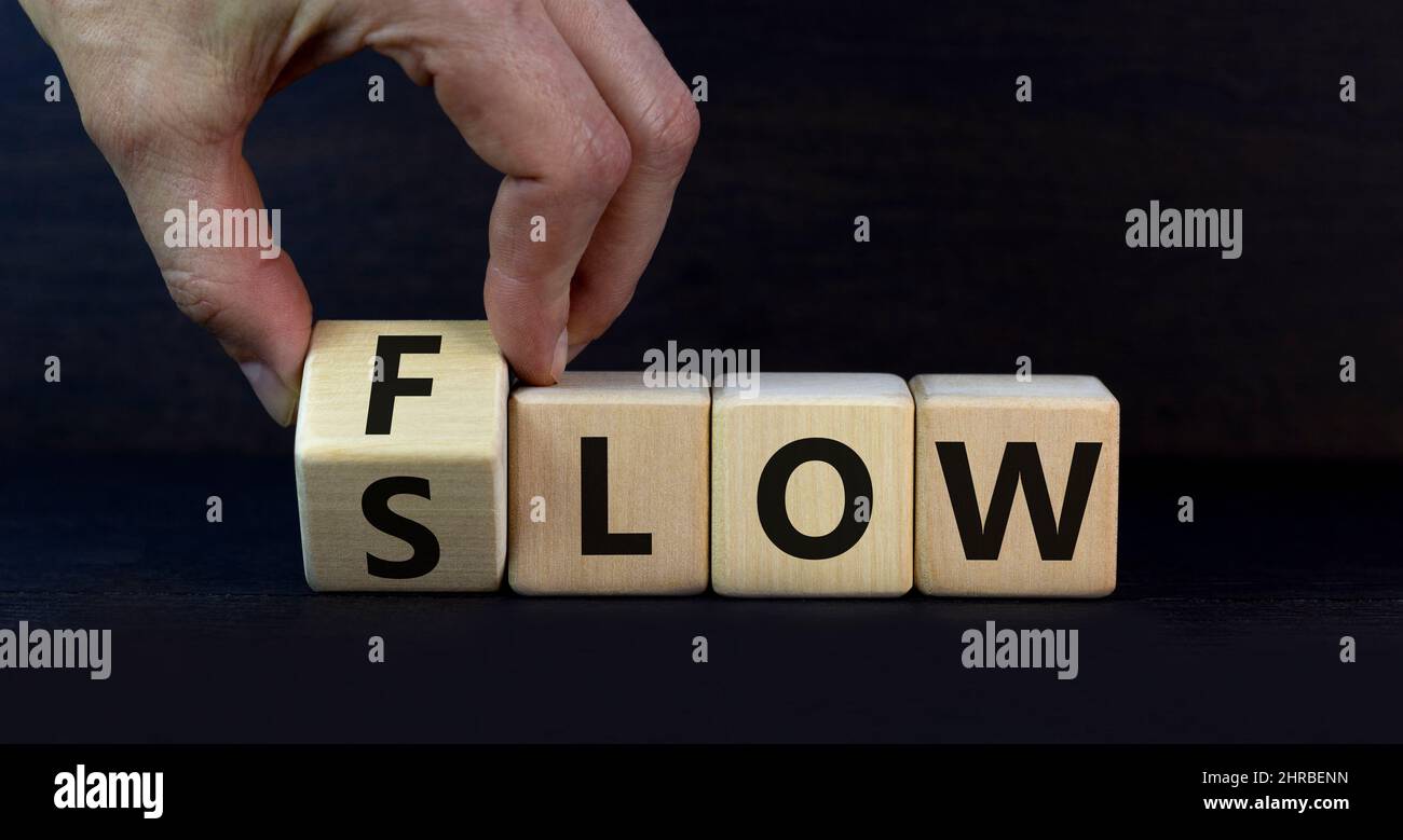 Be slow or in the flow symbol. Businessman turns a wooden cube and ...