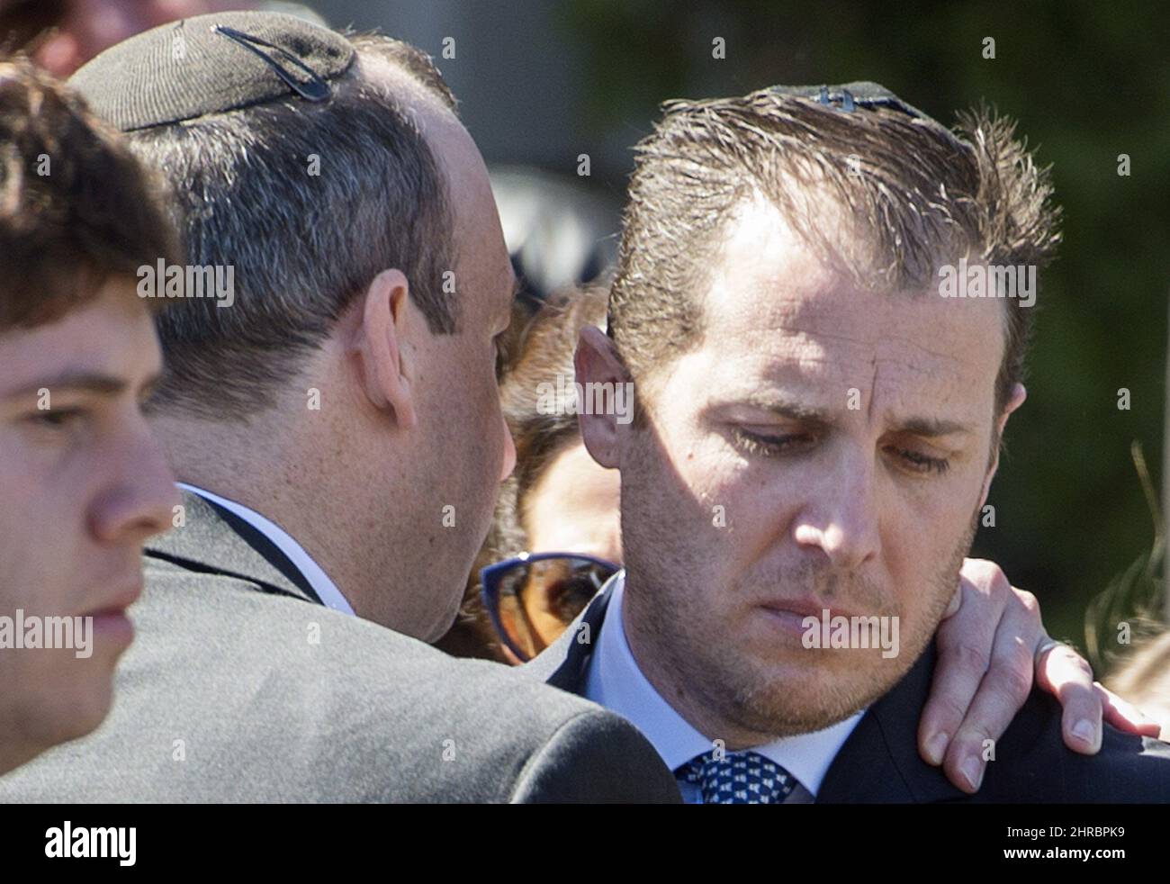 A family member of Dr. Mark Wainberg is consoled outside the synagogue ...