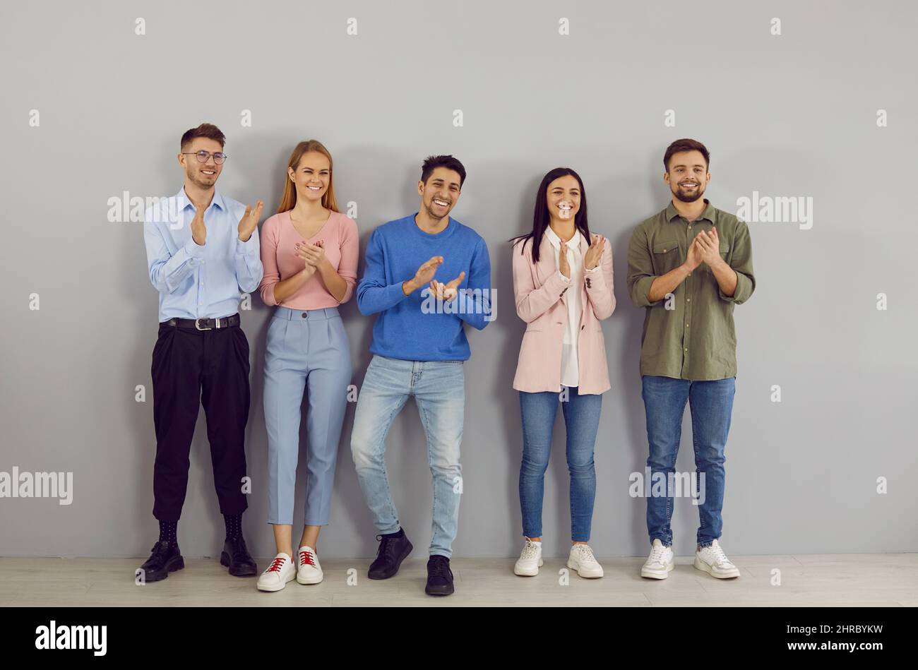 Friendly and happy young successful people stand in line and applaud ...