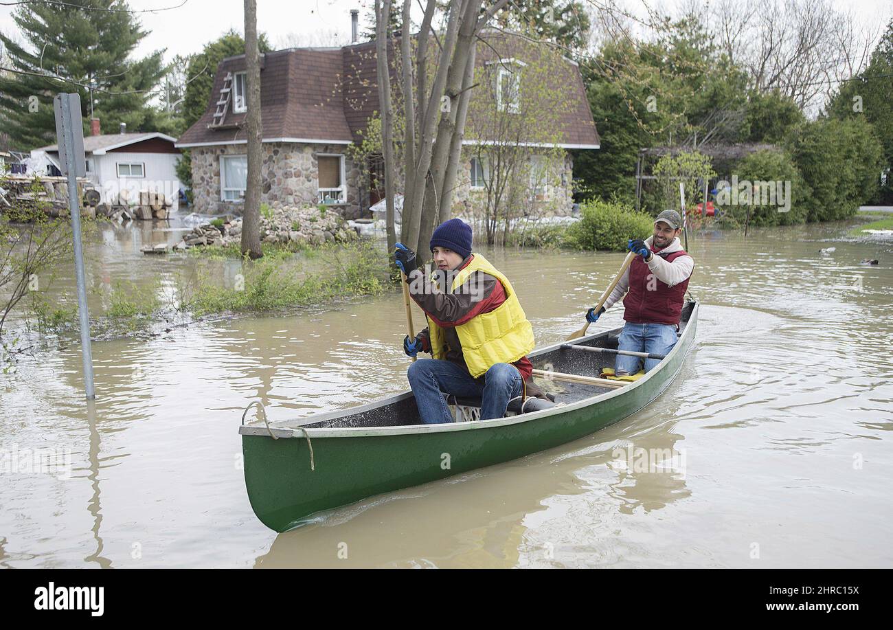 Two men paddle a canoe along a street surrounded by floodwaters in the ...