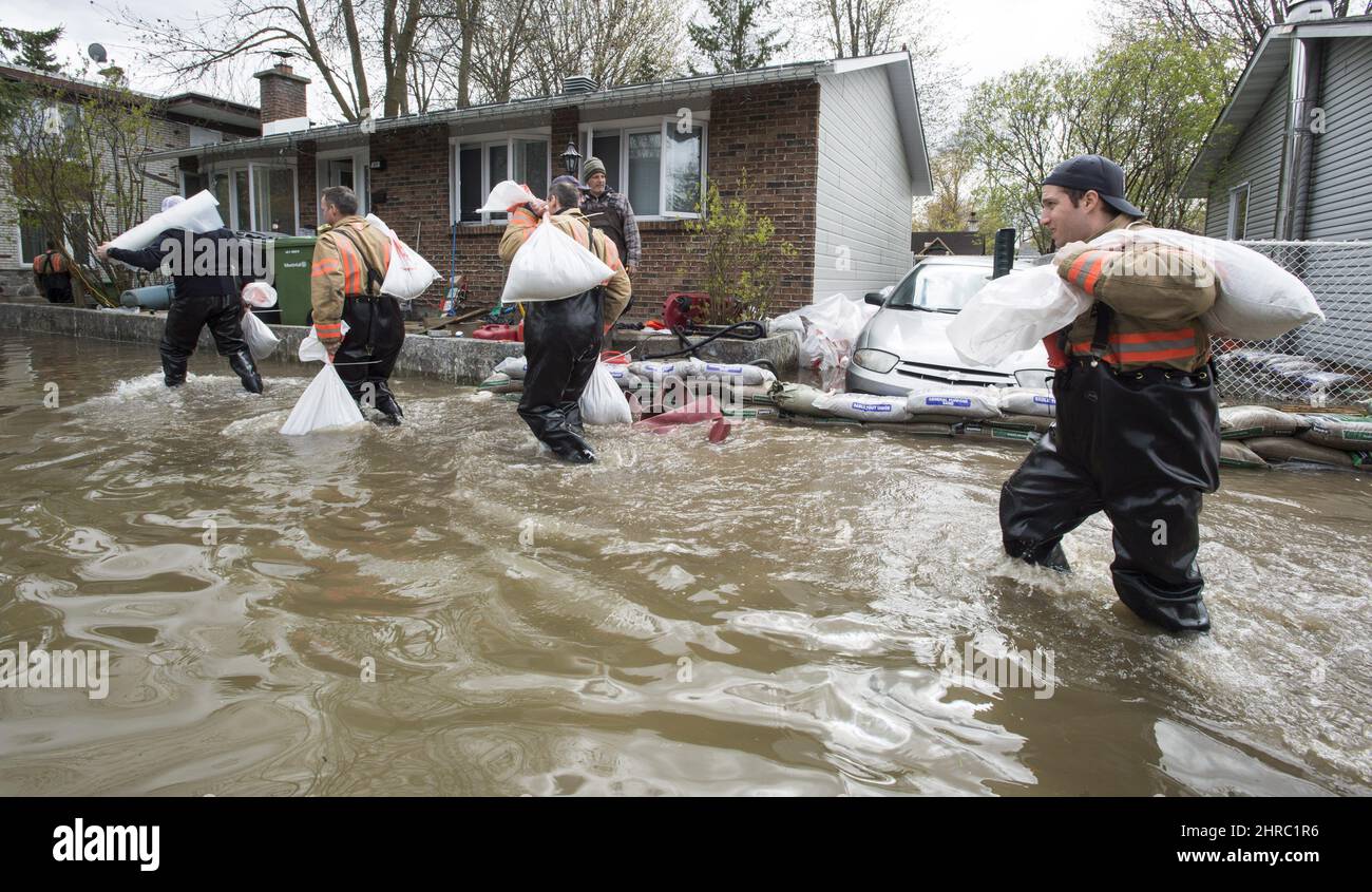 Firemen carry sandbags to protect a house on Ile Bizard on the northern ...