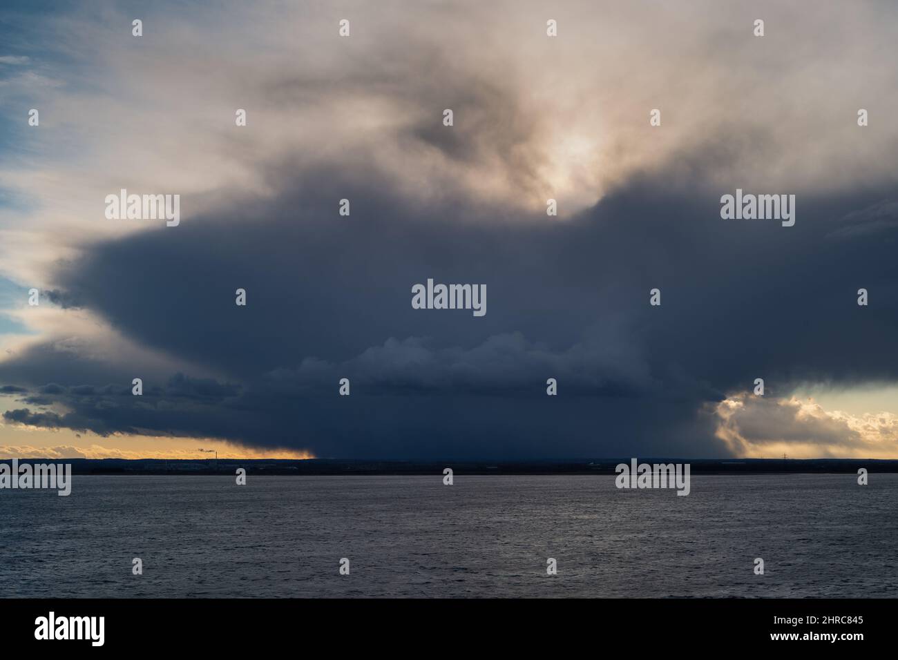 A dramatic image of a rain cloud on the horizon above the sea and a ...