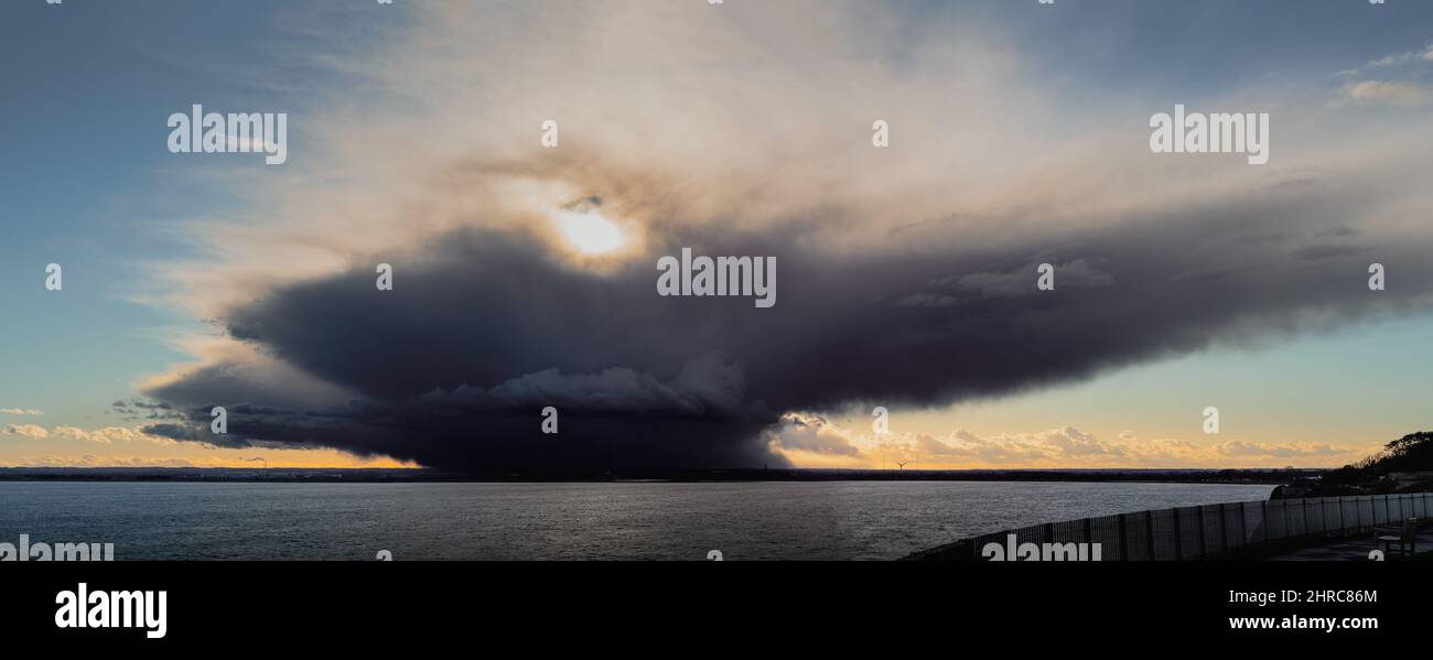 A dramatic panoramic image of a rain cloud on the horizon above the sea ...