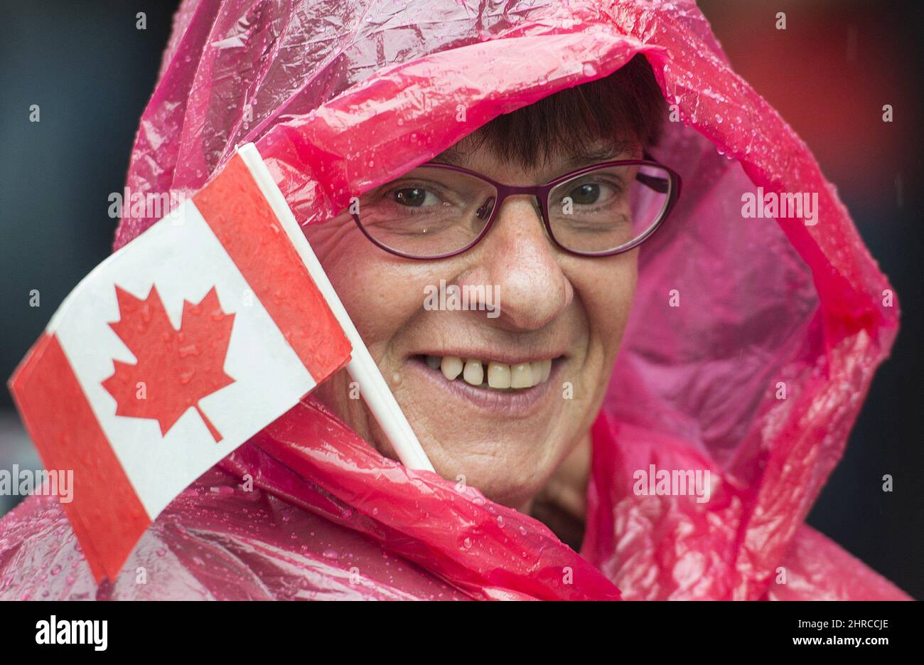 A woman covers up in the rain as she watches the annual Canada Day ...