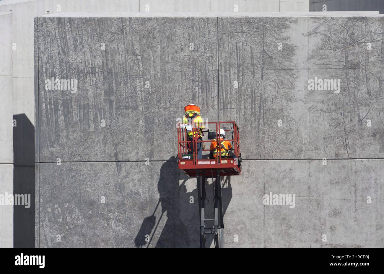 An artist works on etching a design into the concrete form of the ...