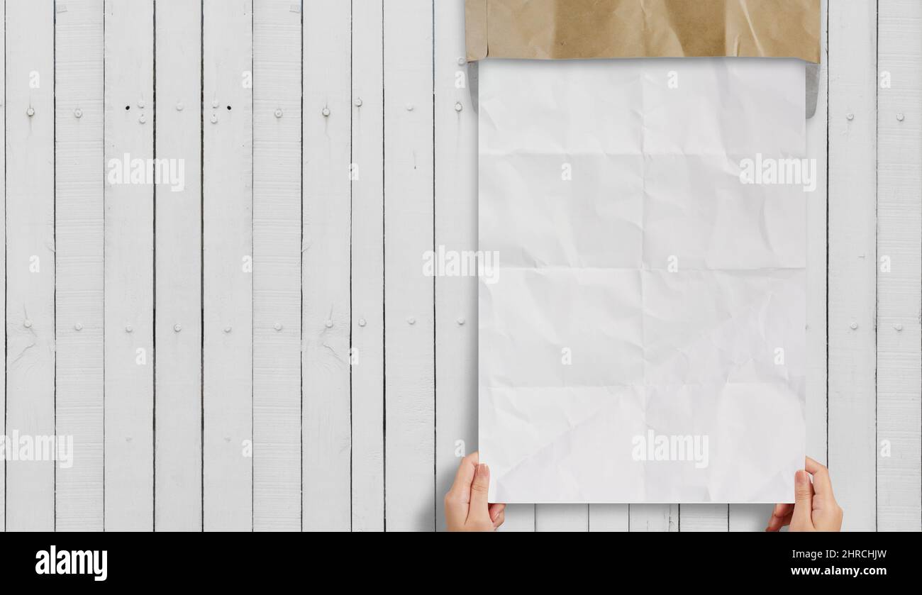 hand pulling crumpled paper from recycle envelope on white wood ...