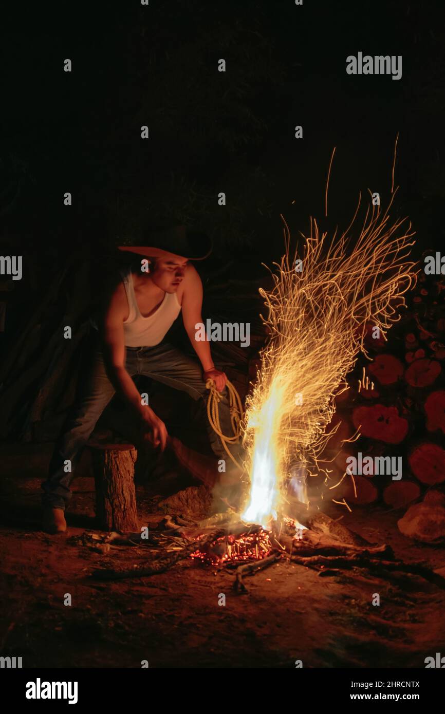 Vertical shot of a cowboy lighting the bonfire in the evening in ...