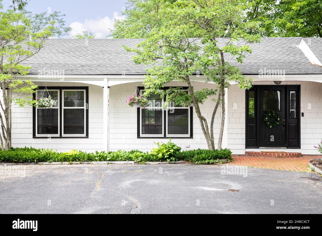 A beautiful farmhouse ranch with white siding and a black front door ...