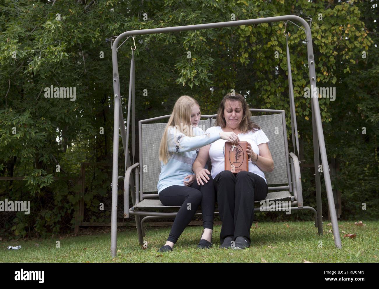 Denise Lane and her daughter Megan sit with the urn containing the ...