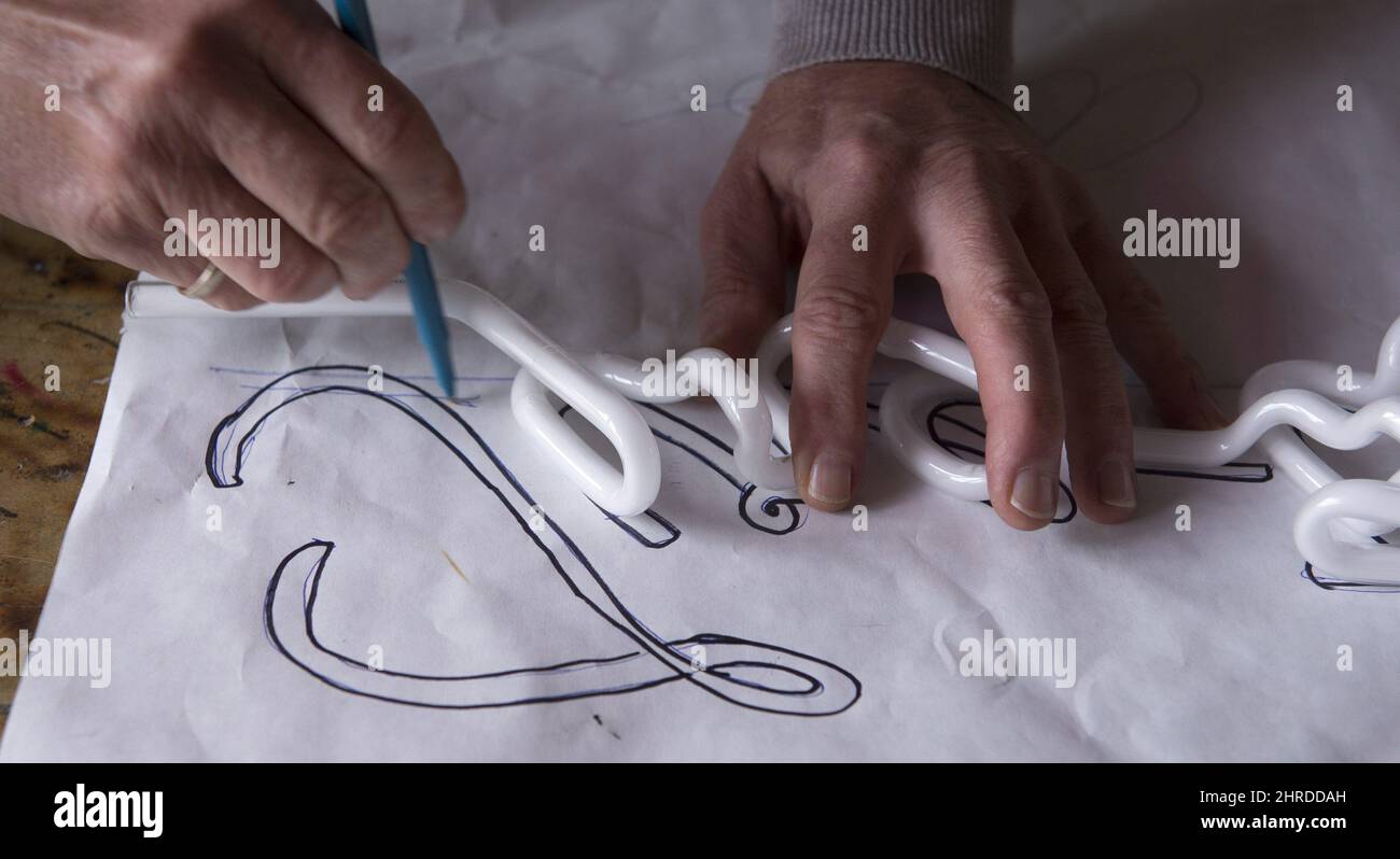 Glass artist Gerald Collard matches the lettering of a neon sign with ...