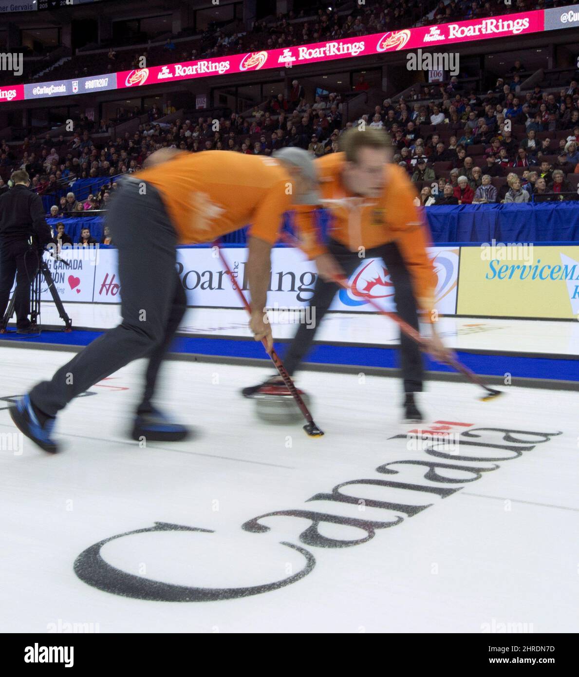 Players sweep the ice ahead of a rock during the Canadian Olympic ...
