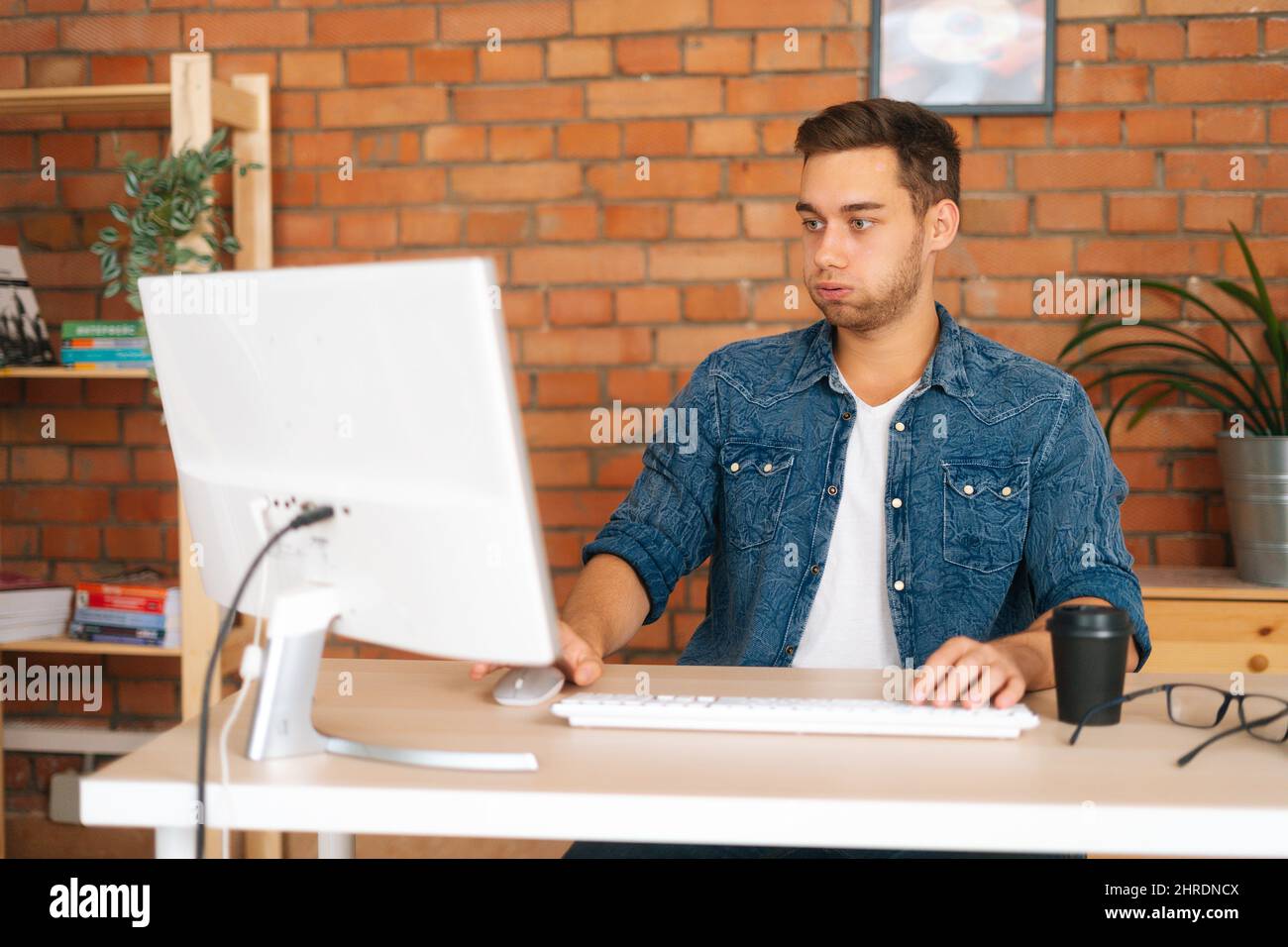 Front view of overworked bored young freelance programmer working on ...