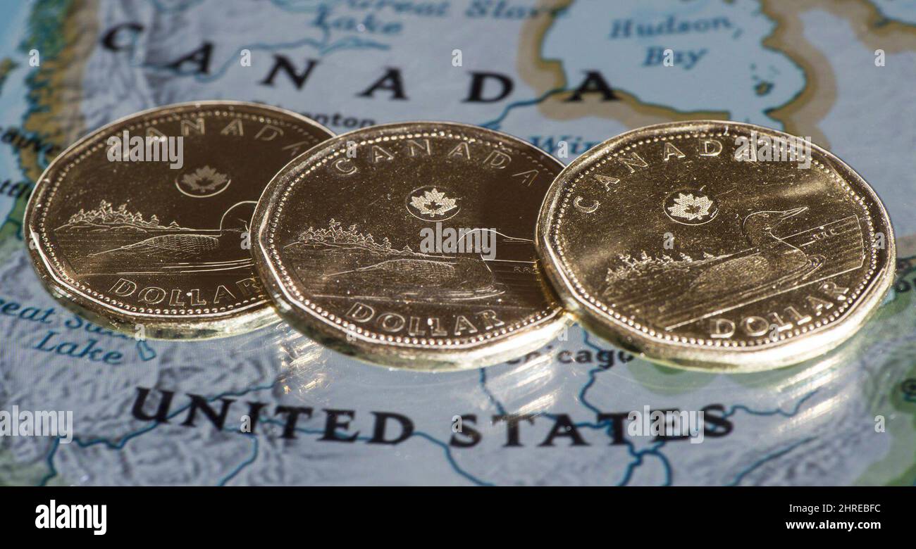 Canadian dollar coins are displayed on a map along the border of Canada ...
