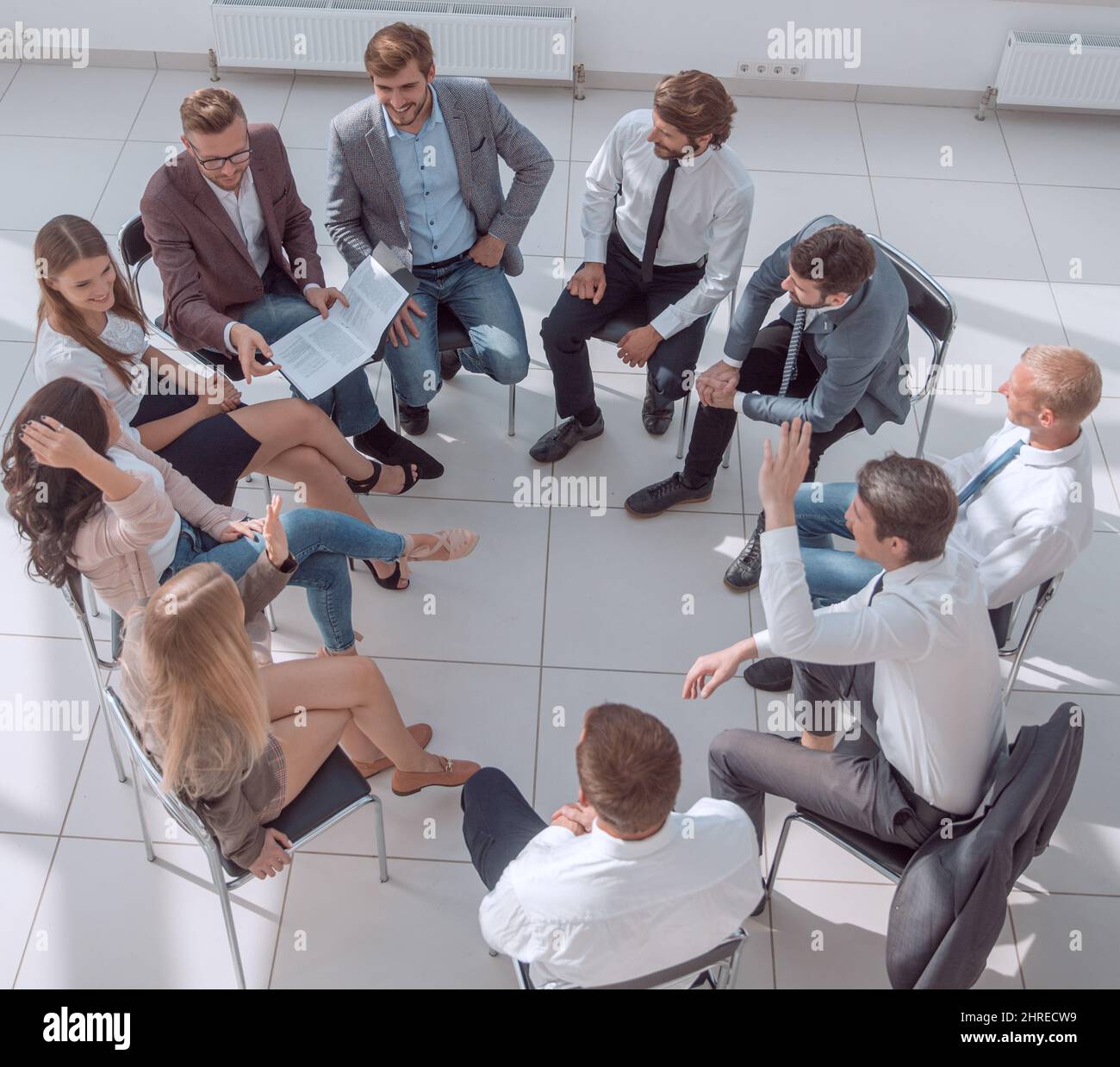 team of young employees sitting in a circle in the conference room ...