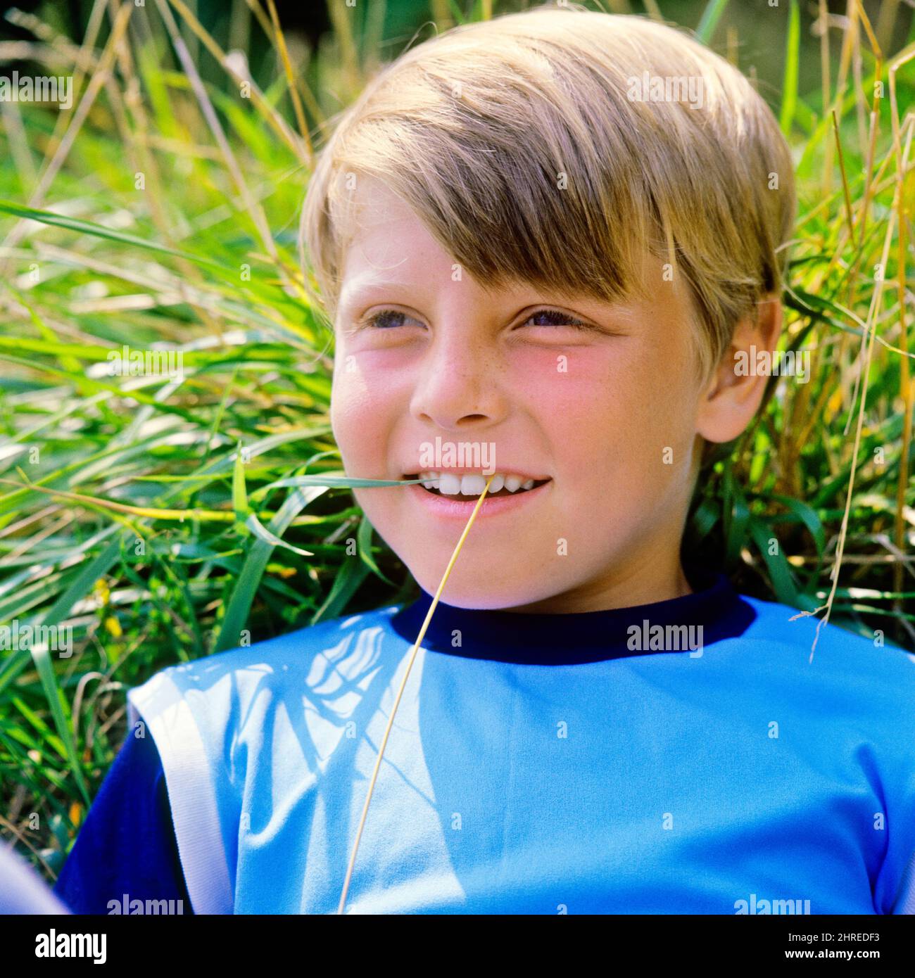 1970s PORTRAIT OF YOUNG BLONDE BOY PIECE OF TALL GRASS IN HIS MOUTH ...