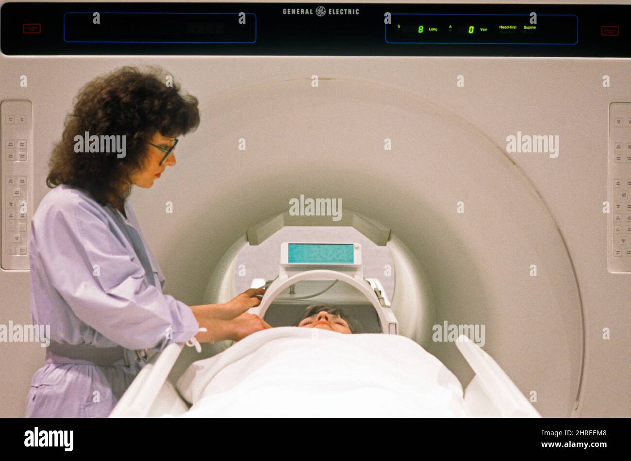 1980s MEDICAL TECHNICIAN WITH PATIENT OPERATING A NUCLEAR MAGNETIC ...