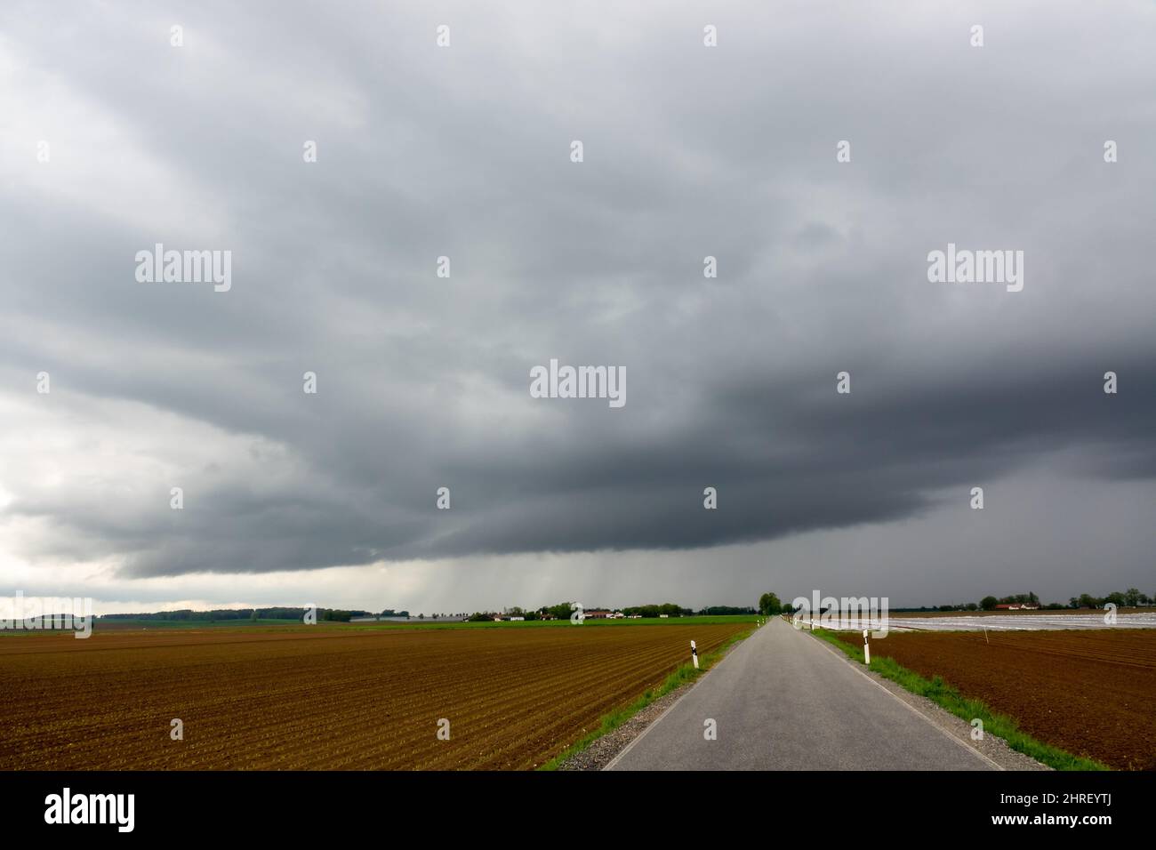 Street with field on both sides and a cloudy sky Stock Photo - Alamy