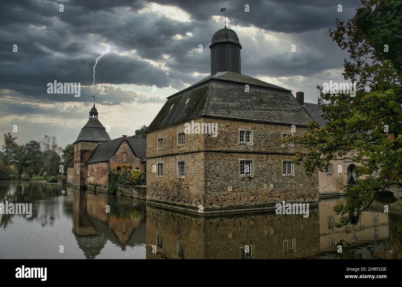 Moated castle in dramatic sky with lightning in background. Beautiful ...