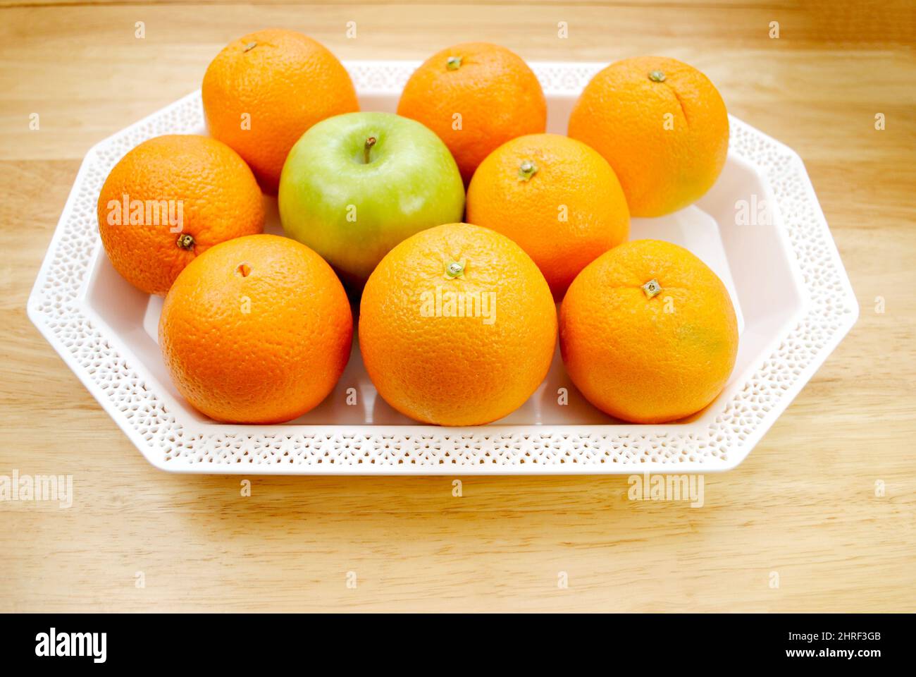 Multiple Oranges on a White Platter with One Green Apple Stock Photo ...