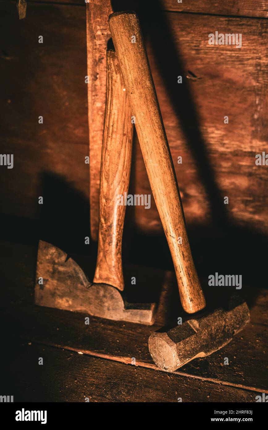 Vertical shot of an old handmade hammer and ax with wooden handles ...