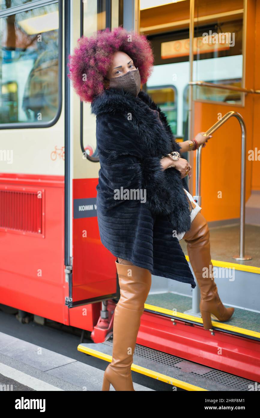 Red hair African woman posing for the camera while getting on the bus ...