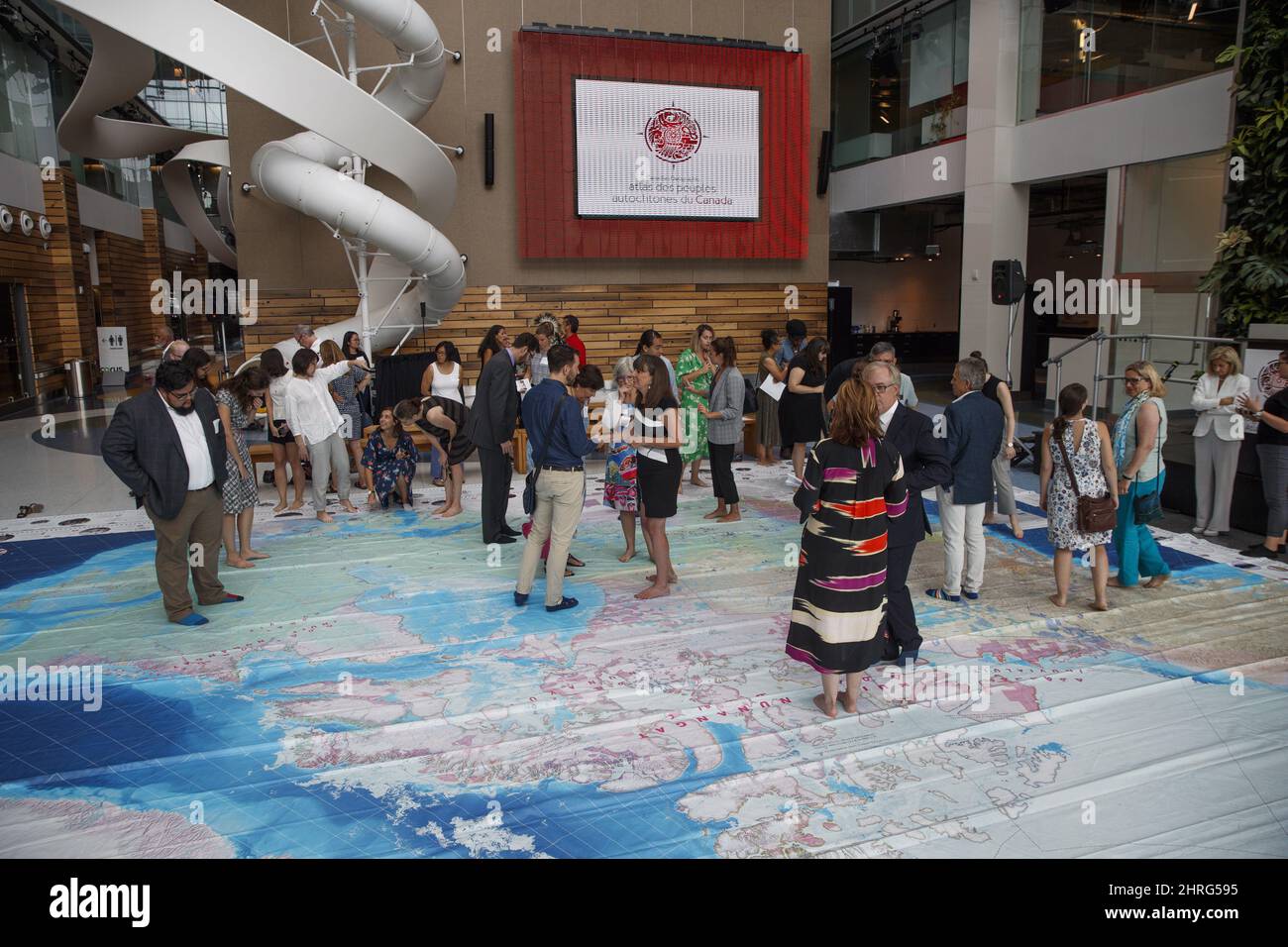 People stand on a giant map from the Indigenous Peoples Atlas of Canada ...