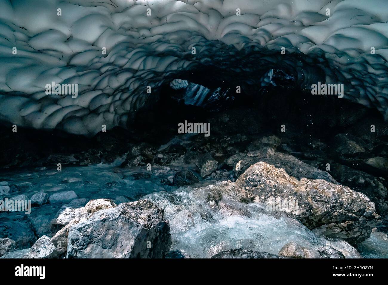 Beautiful ice cave with rocks and stream of hot water in Kamchatka ...
