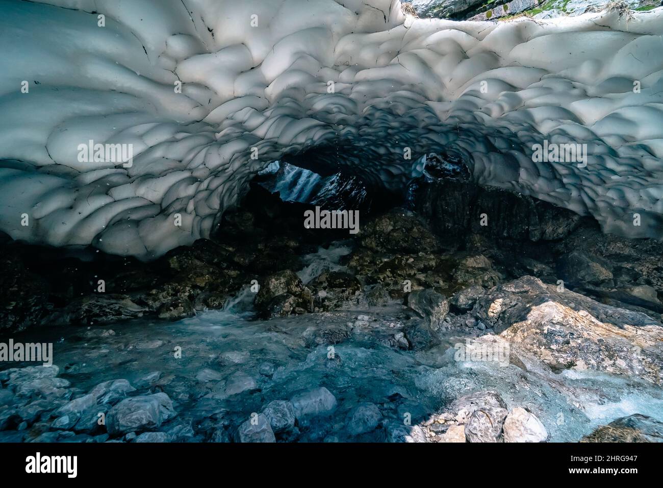 Beautiful ice cave with rocks and stream of hot water in Kamchatka ...