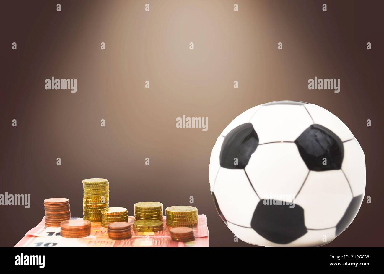 Football and Euro banknotes and golden coins with blurred brown lights ...