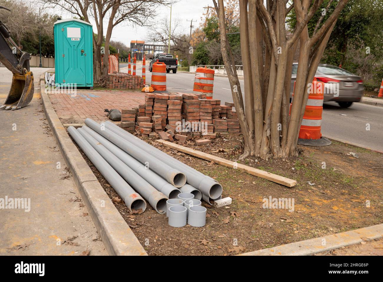 Construction site on city street with materials, portable toilet, tree ...