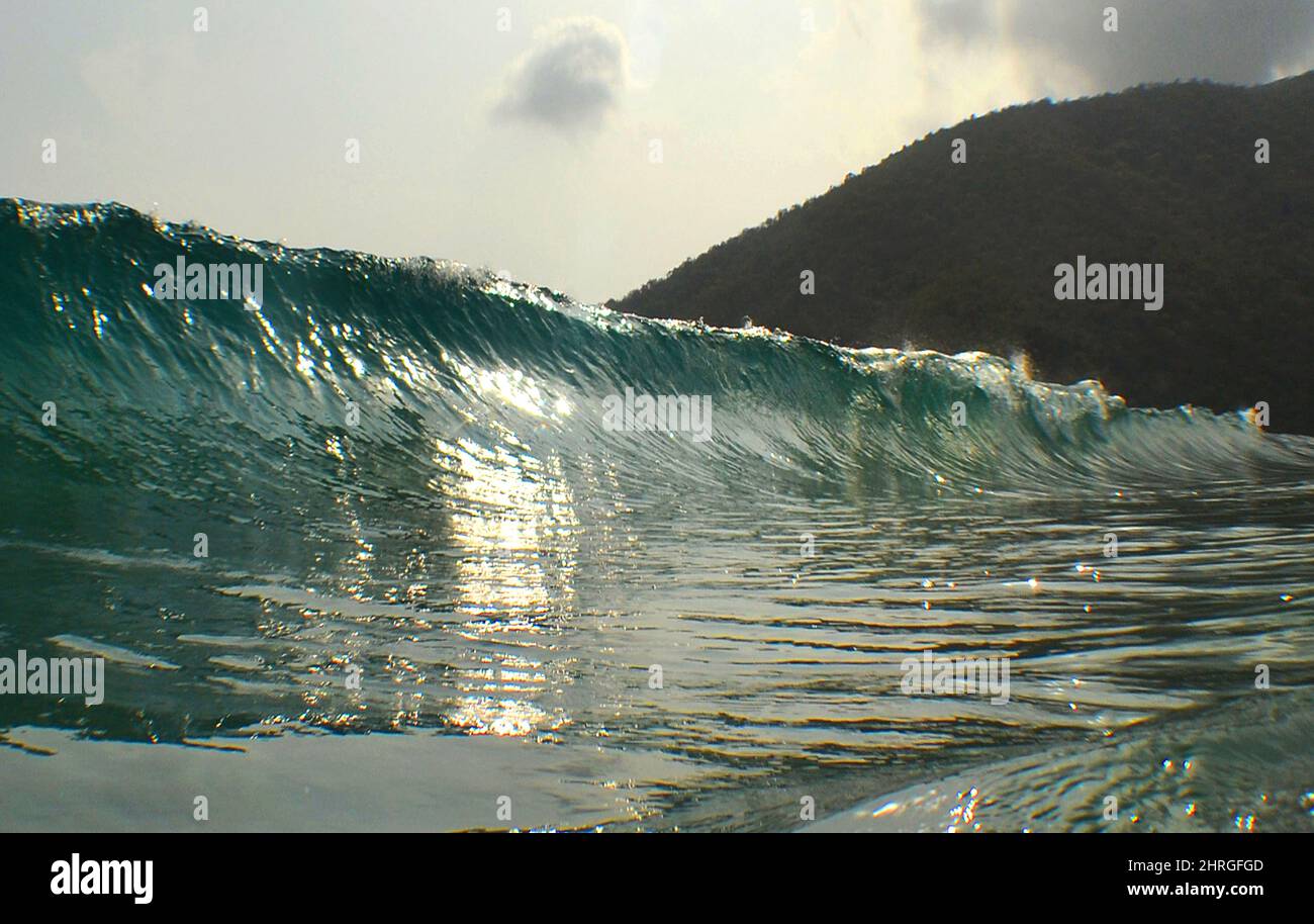 Beautiful scene of high shiny waves with silhouetted mountain and light ...