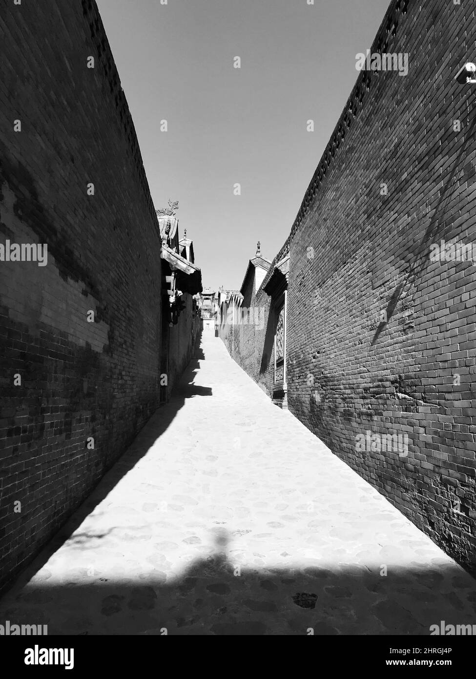 Grayscale of a narrow path between brick walls Stock Photo - Alamy
