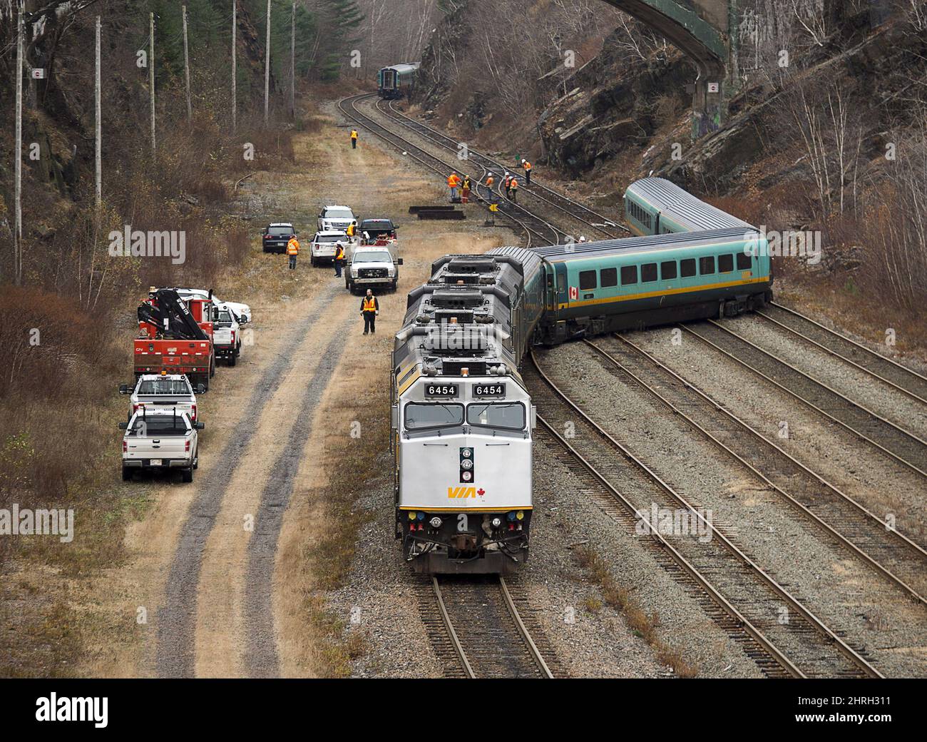 Workers examine the tracks after several VIA rail passenger cars ...