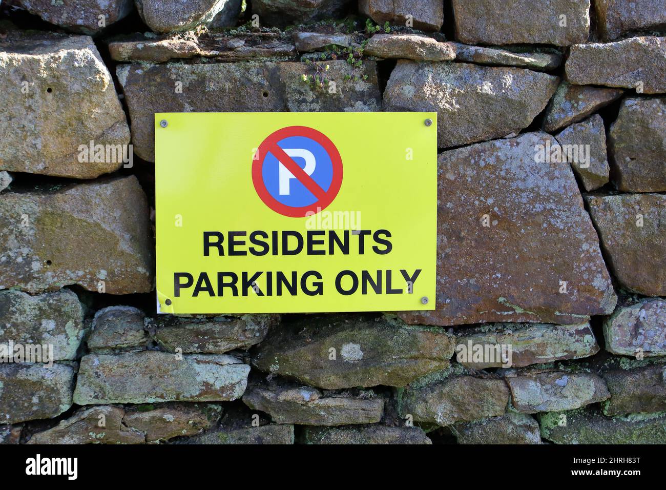 A rectangular residents parking only sign fastern to a dry stone wall ...
