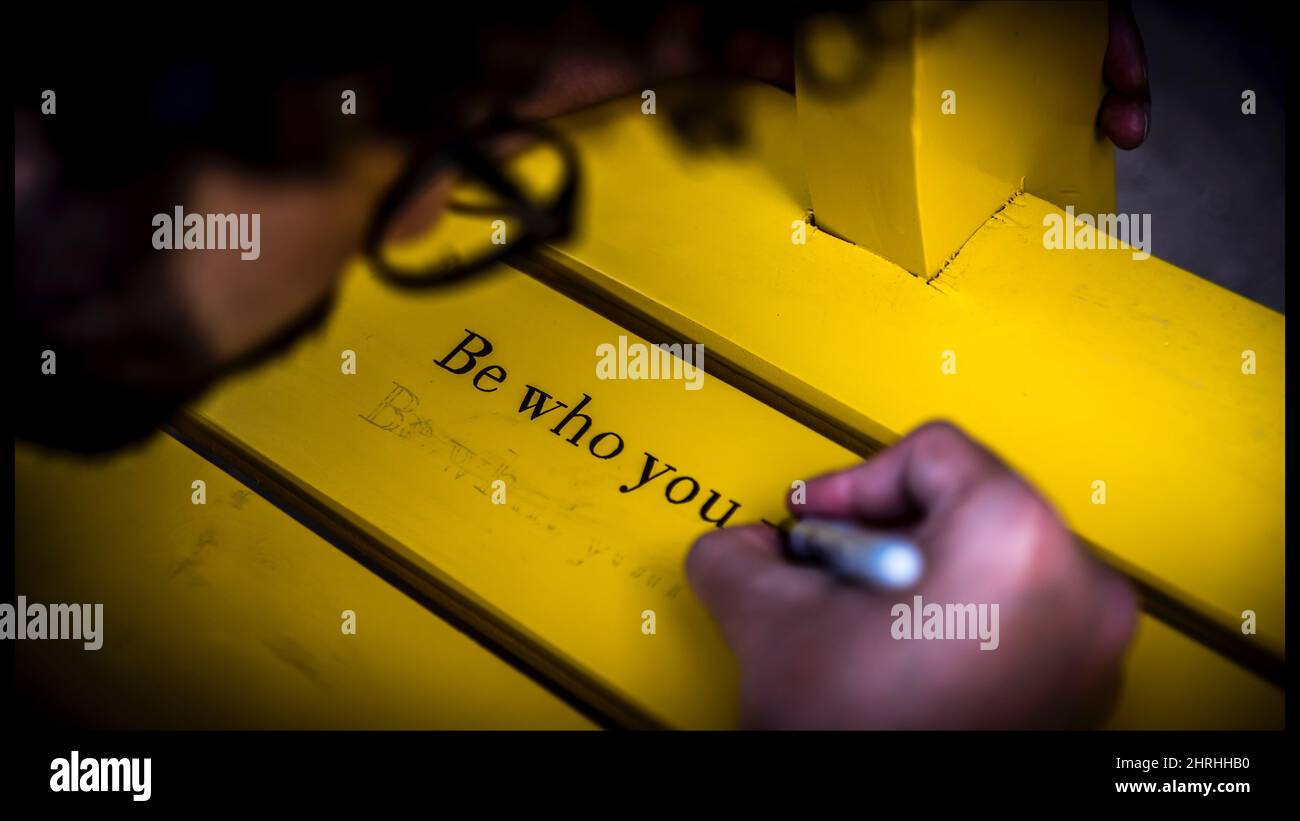Closeup of a guy writing with a marker on a yellow bench Stock Photo ...
