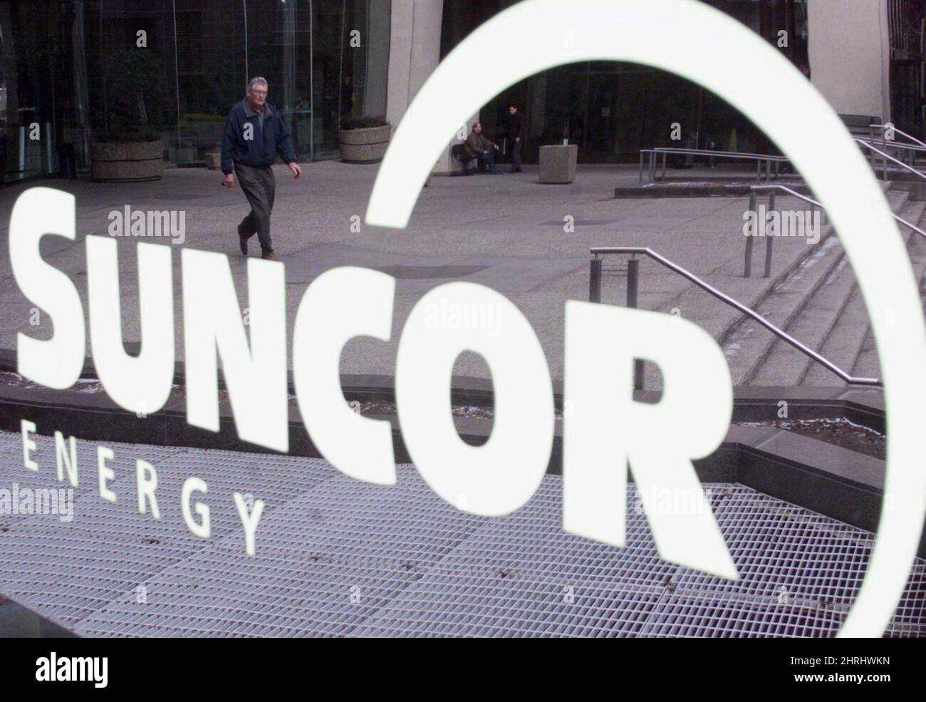 A man is reflected in a sign as he leaves the building where Suncor ...