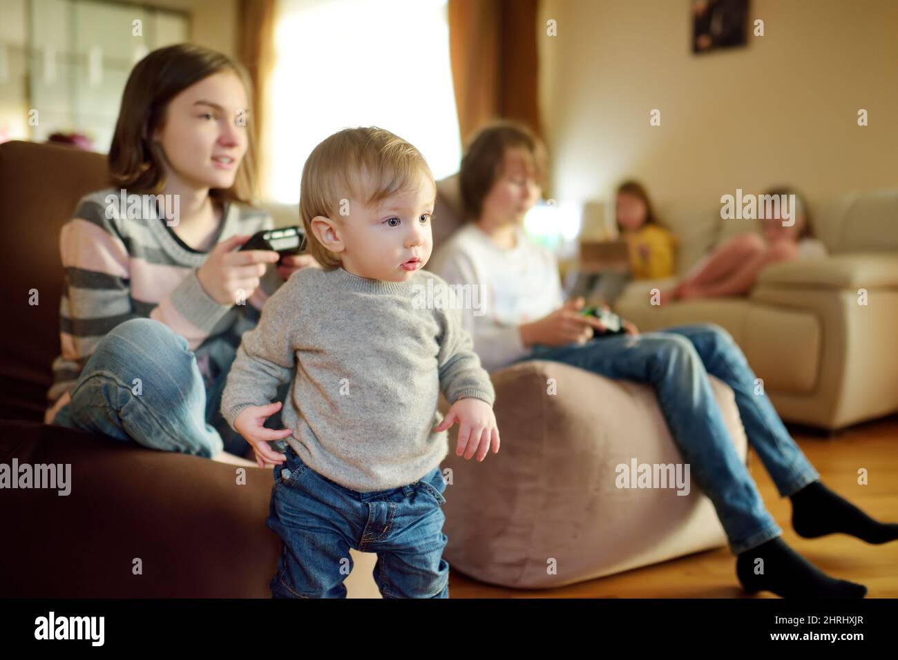 Cute toddler boy watching a group of preteen kids playing video games ...