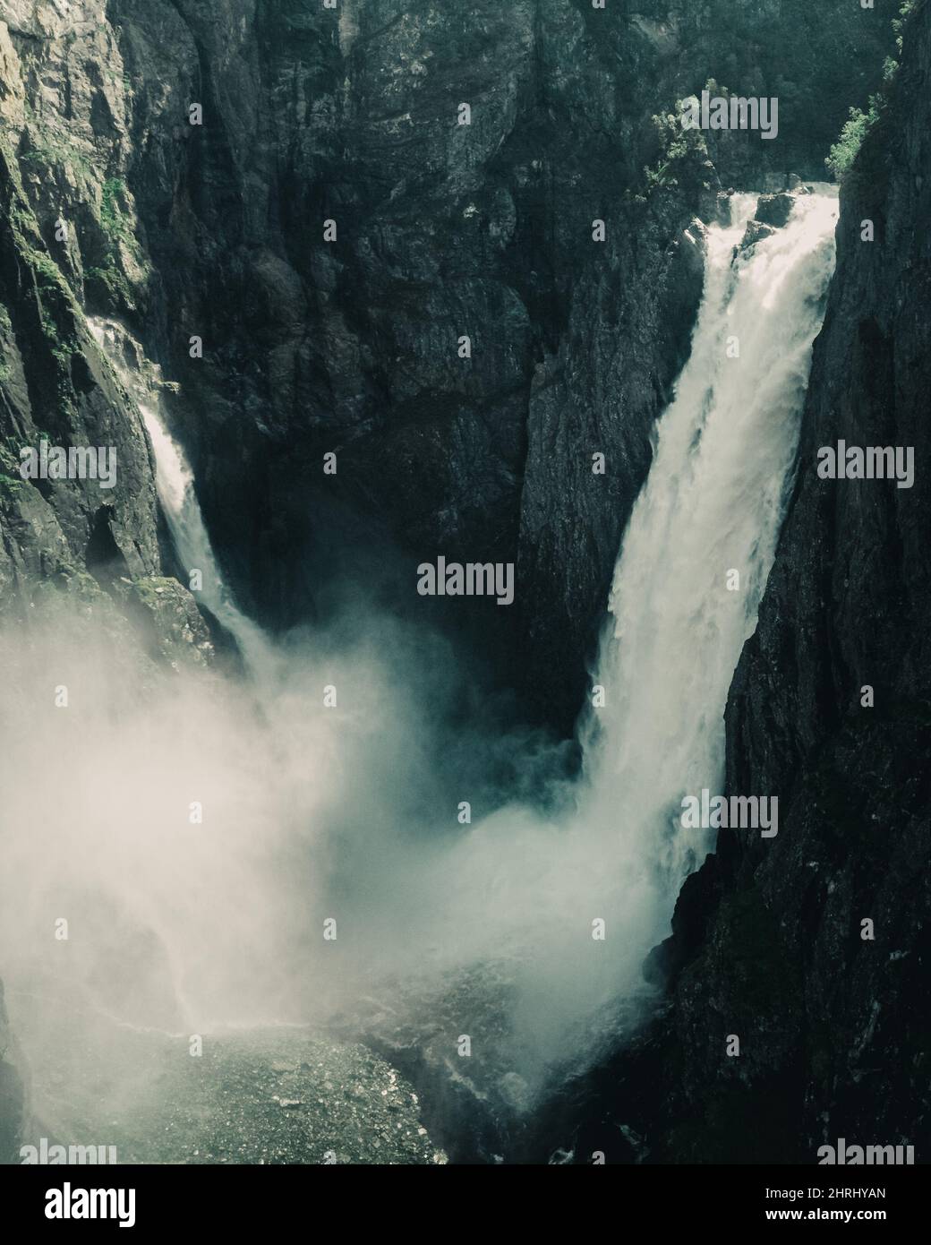 Vertical shot of a waterfall rapidly flowing down from the high cliff ...