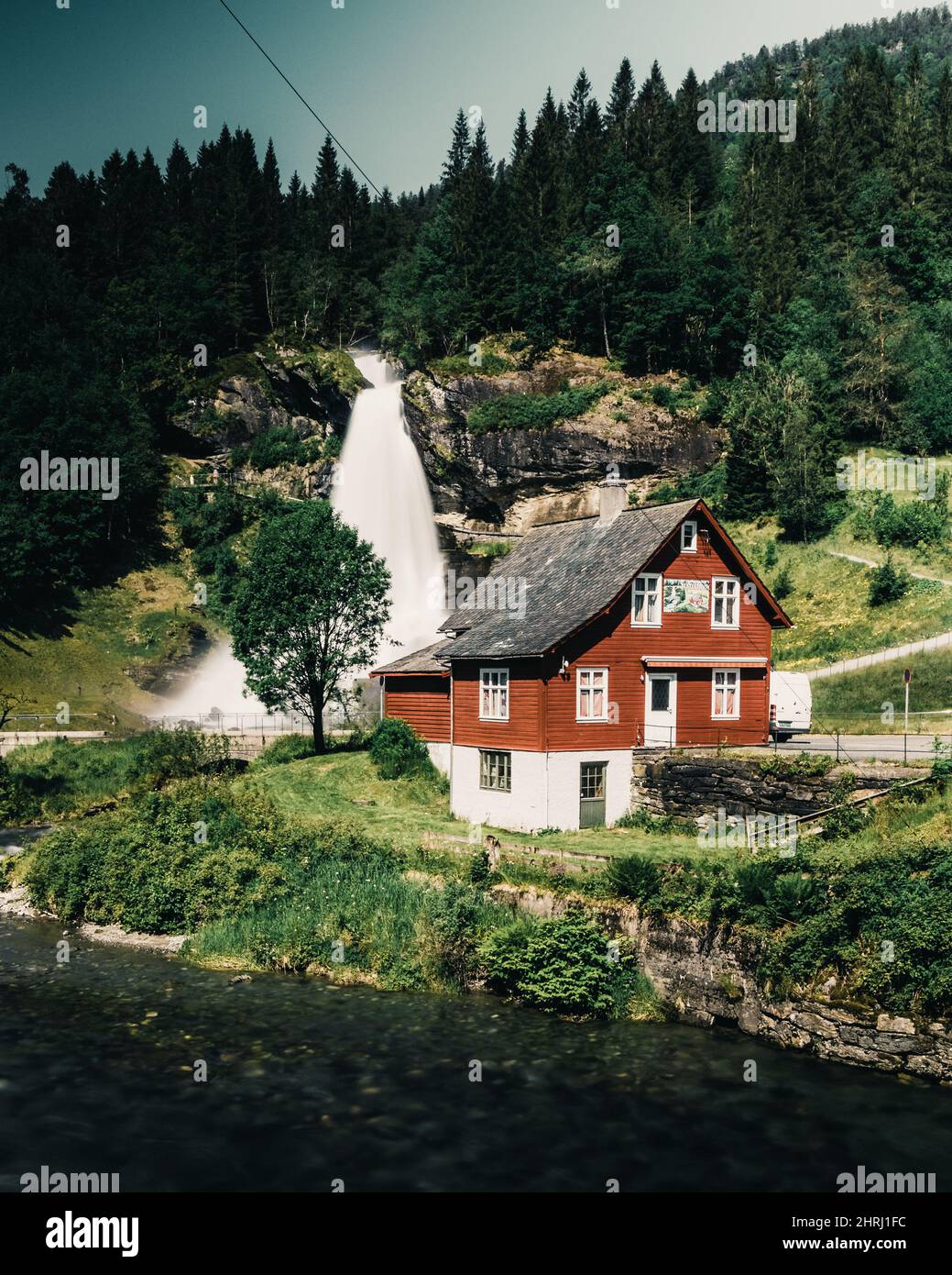 Vertical shot of a red rural building in a green field with trees and a ...