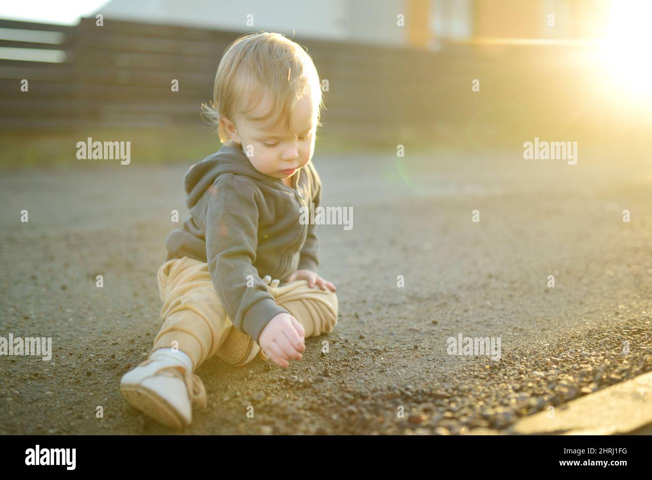 Funny toddler boy sitting on the ground outdoors on sunny summer day ...
