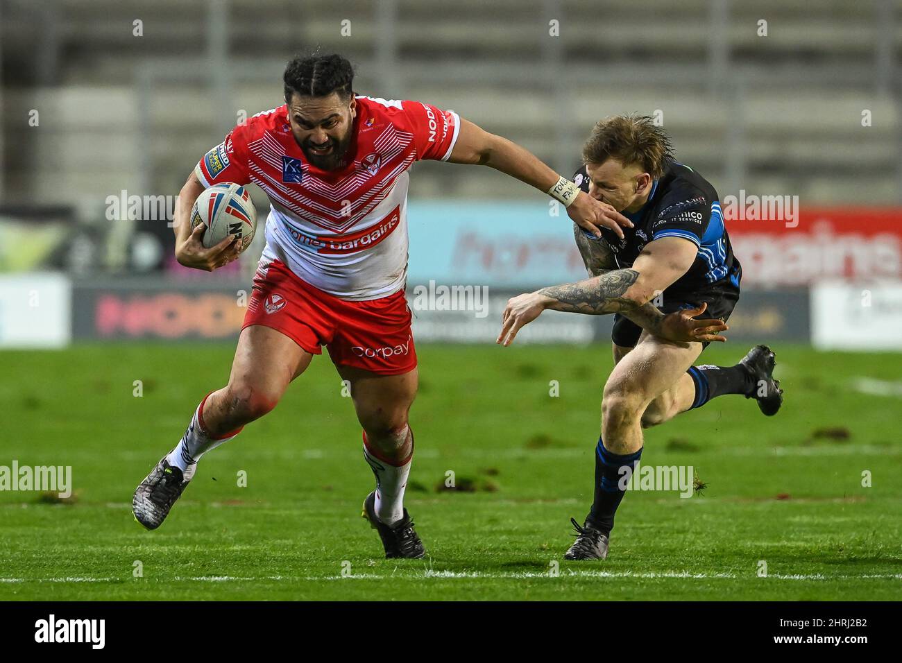 Konrad Hurrell #23 of St Helens breaks the tackle of Tom Johnstone #2 ...