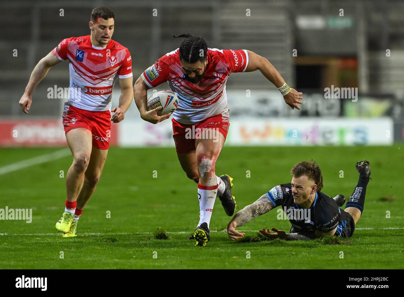 Konrad Hurrell #23 of St Helens breaks the tackle of Tom Johnstone #2 ...