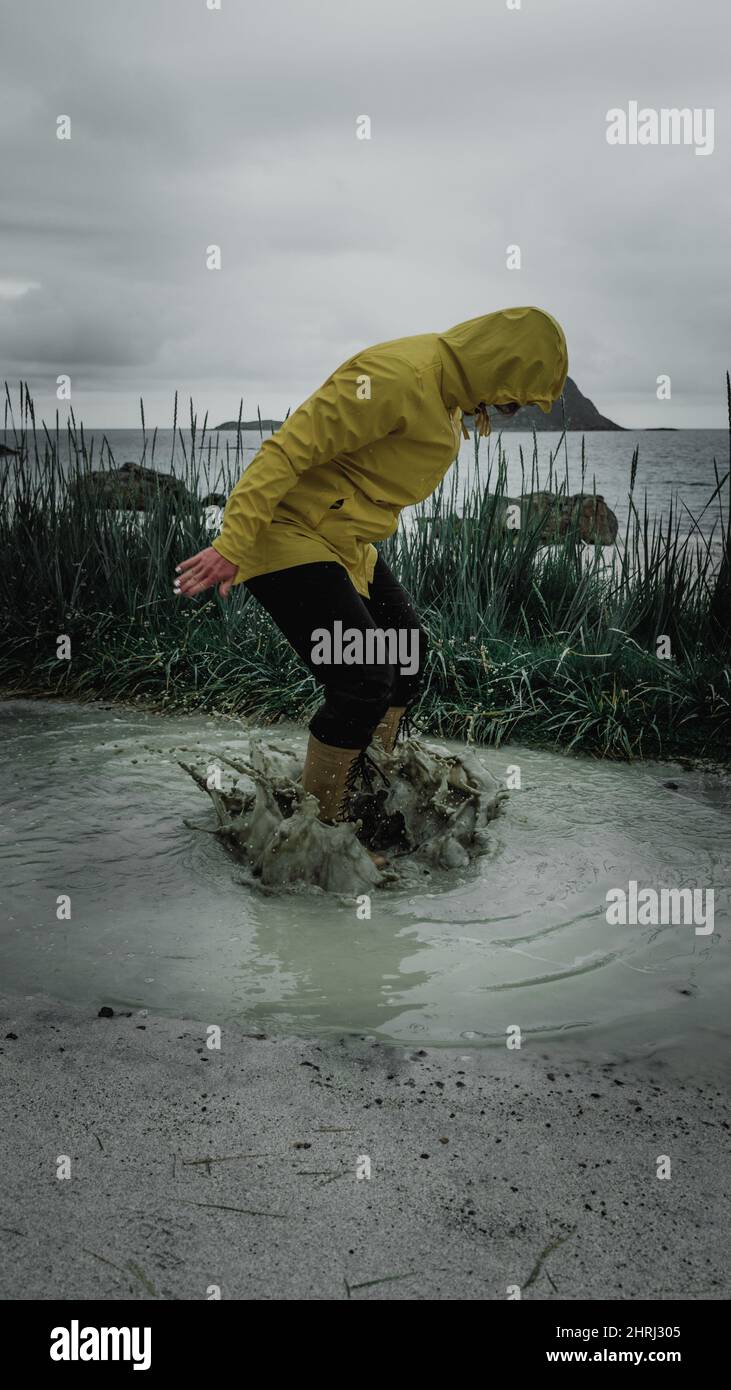 Vertical shot of a person jumping in the mud in rubber boots Stock ...